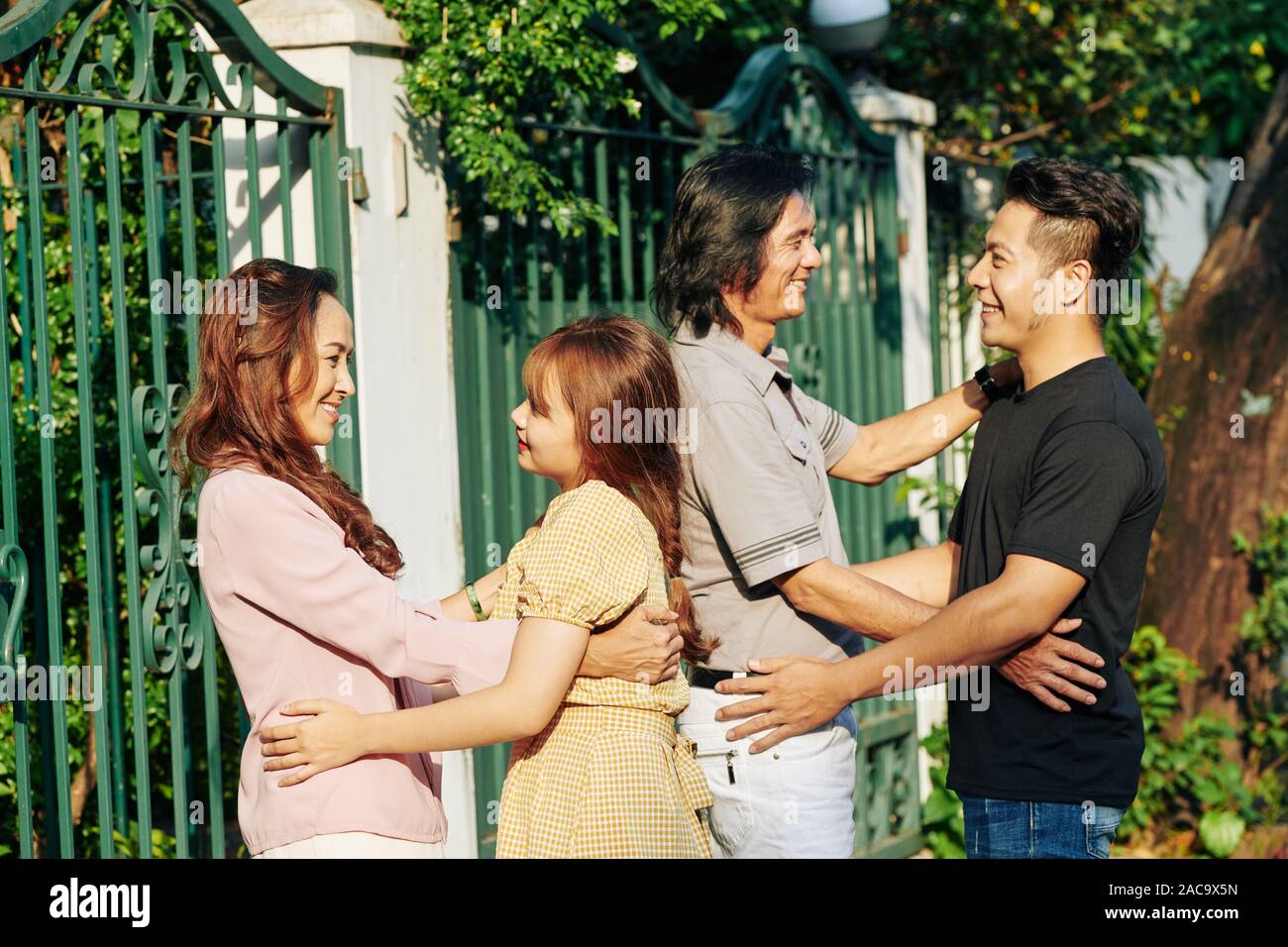 Happy smiling middle-aged parents hugging their daughter and son when ...