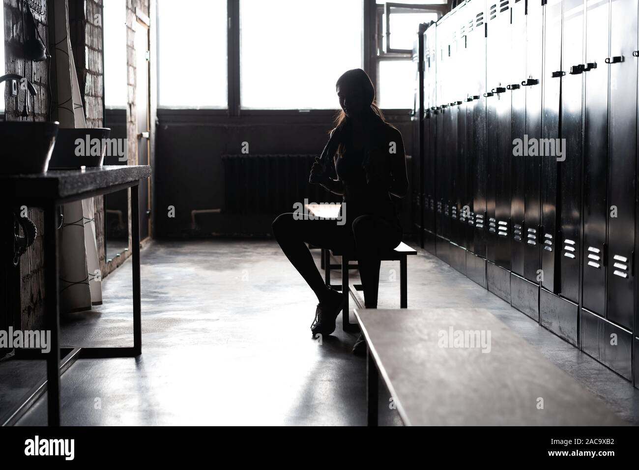 Caucasian female athlete preparing for a workout in a gym locker room ...