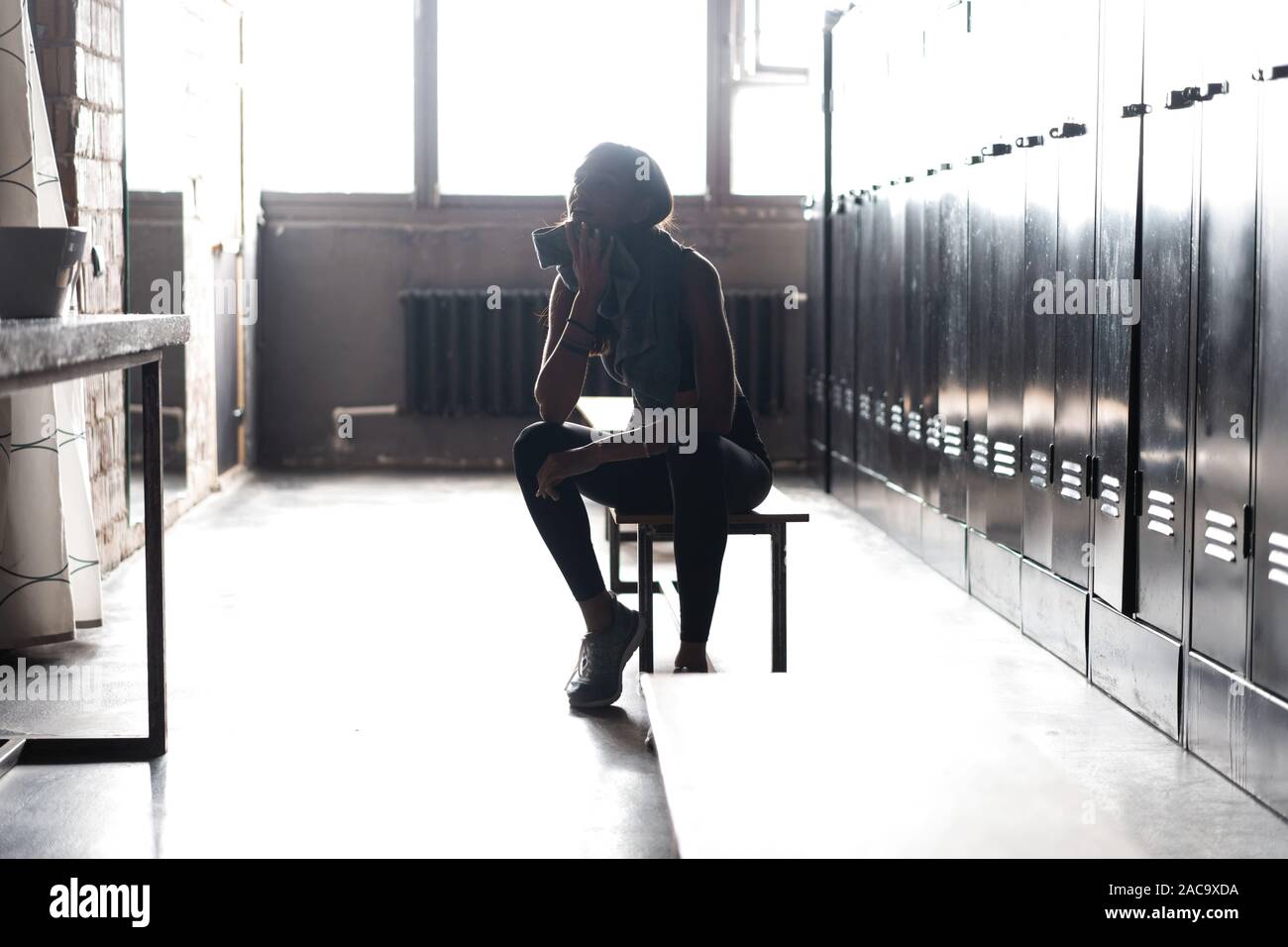 Caucasian female athlete preparing for a workout in a gym locker room ...