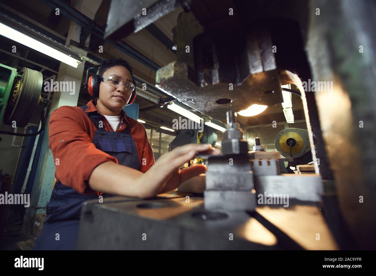 Low angle portrait of modern African-American woman operating machine ...