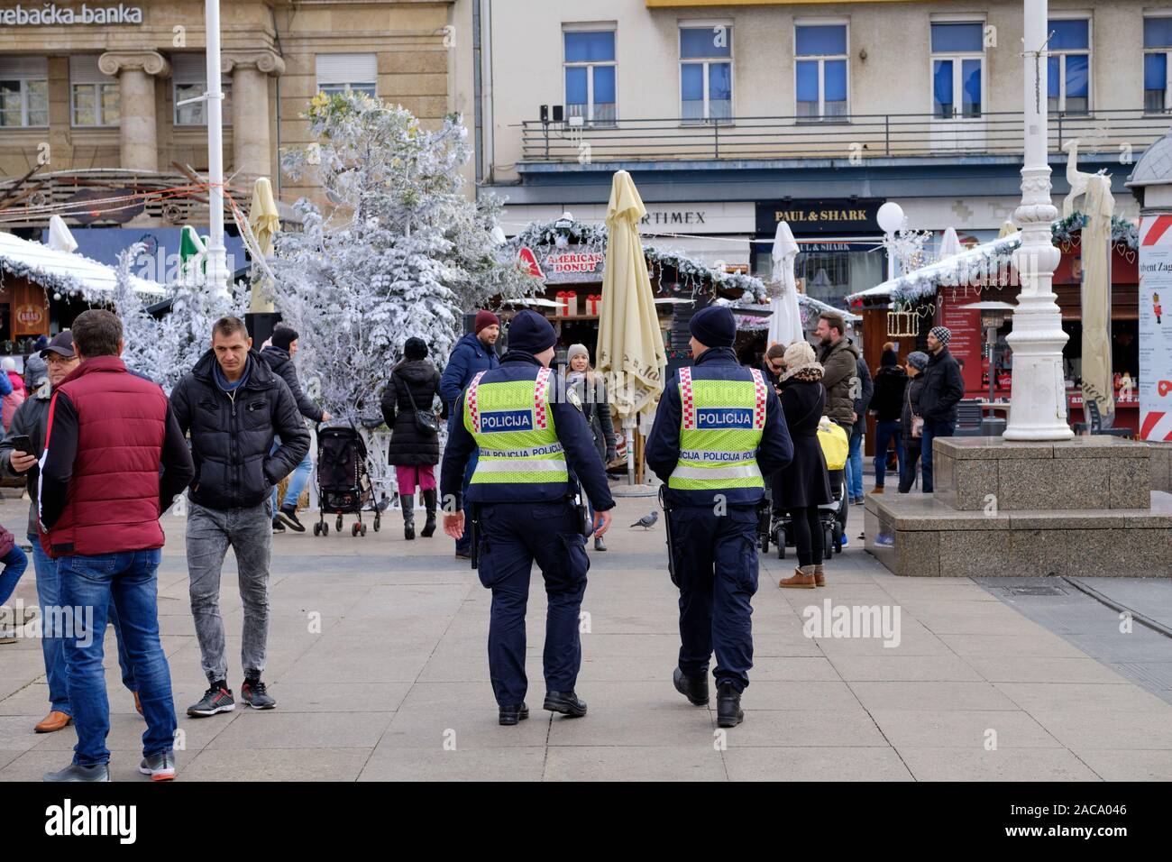 Police in yellow visibility vests viewed from behind walking around ...