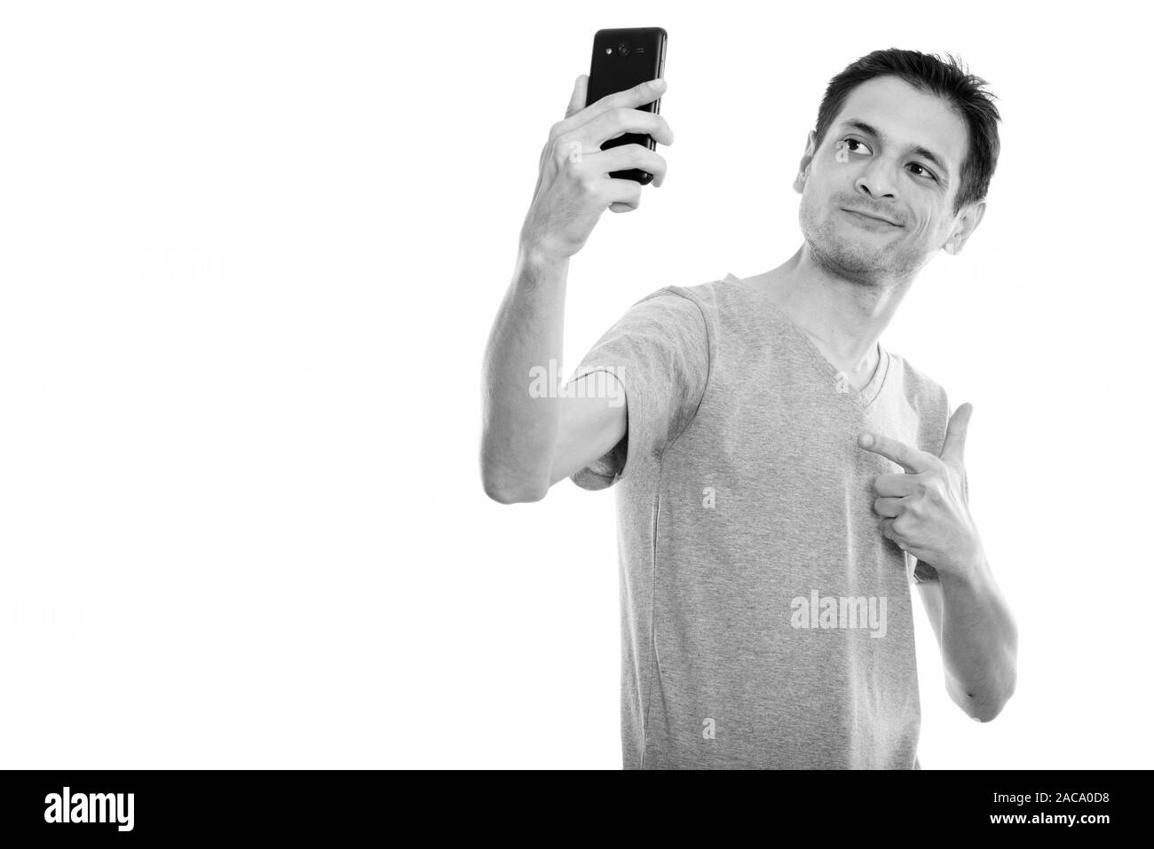 Studio shot of happy young man smiling while taking selfie picture with ...