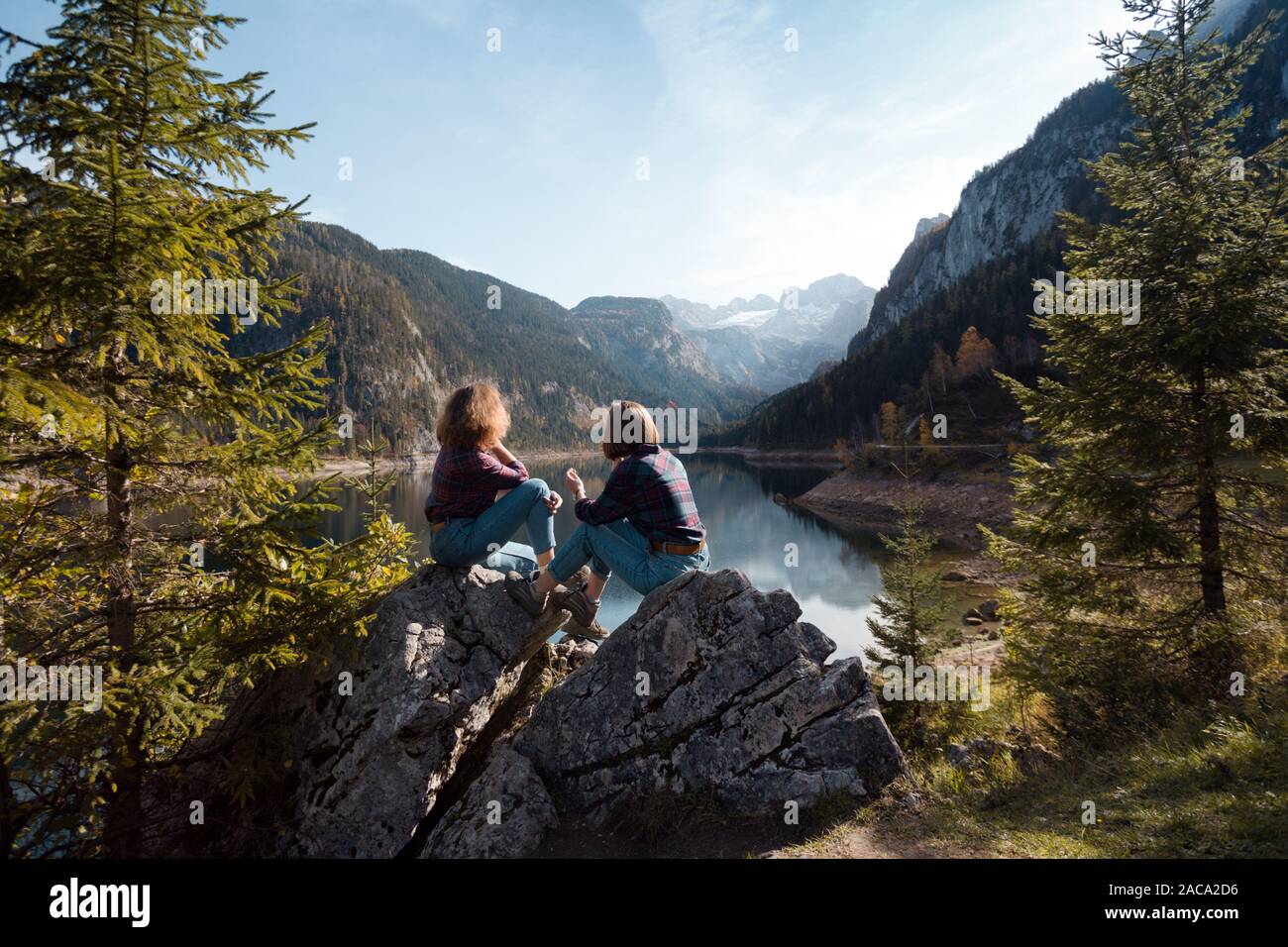 mountain trip. two happy girls on the background of a mountain lake and ...