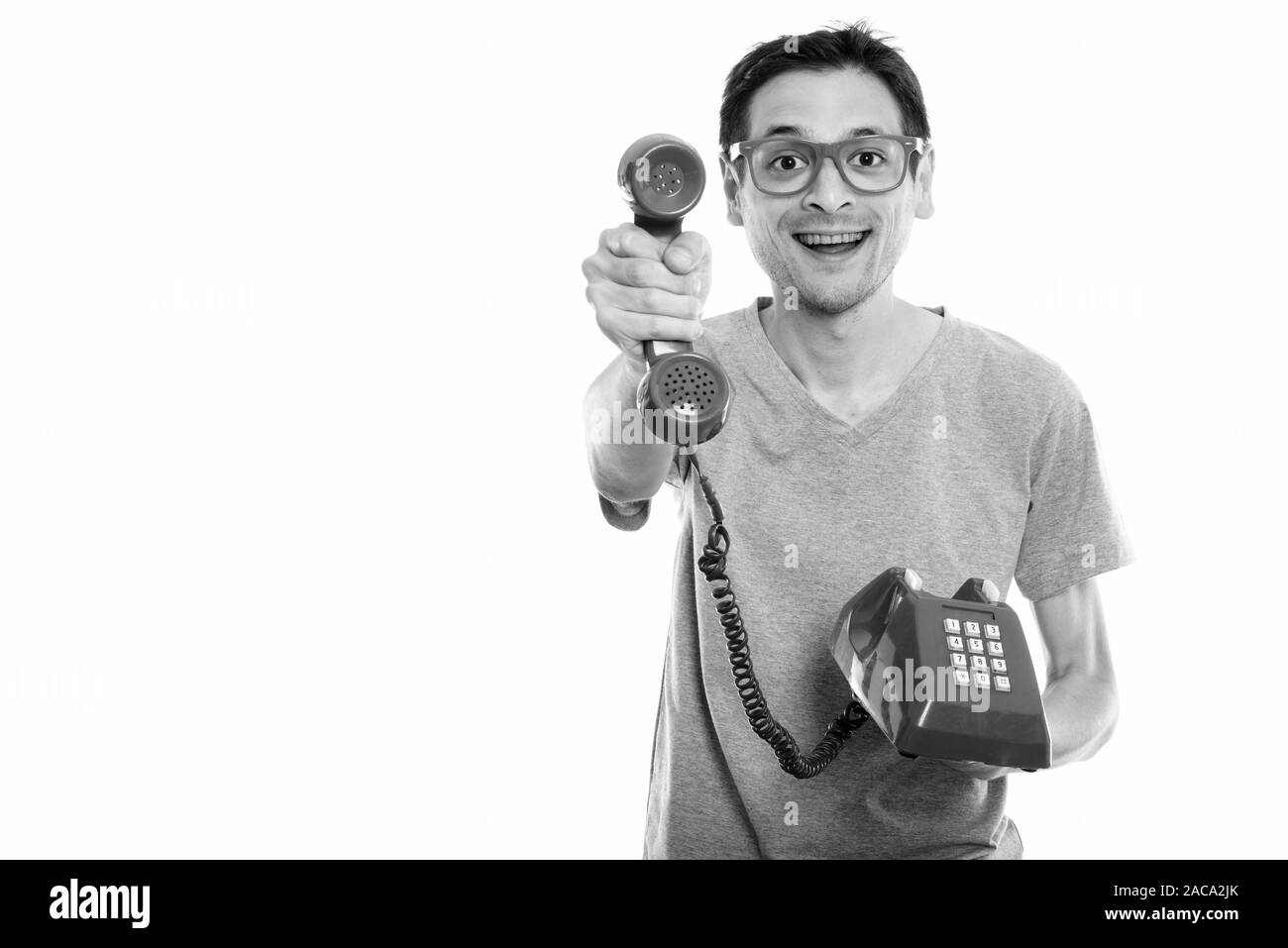 Studio shot of happy young man smiling while giving old telephone Stock ...