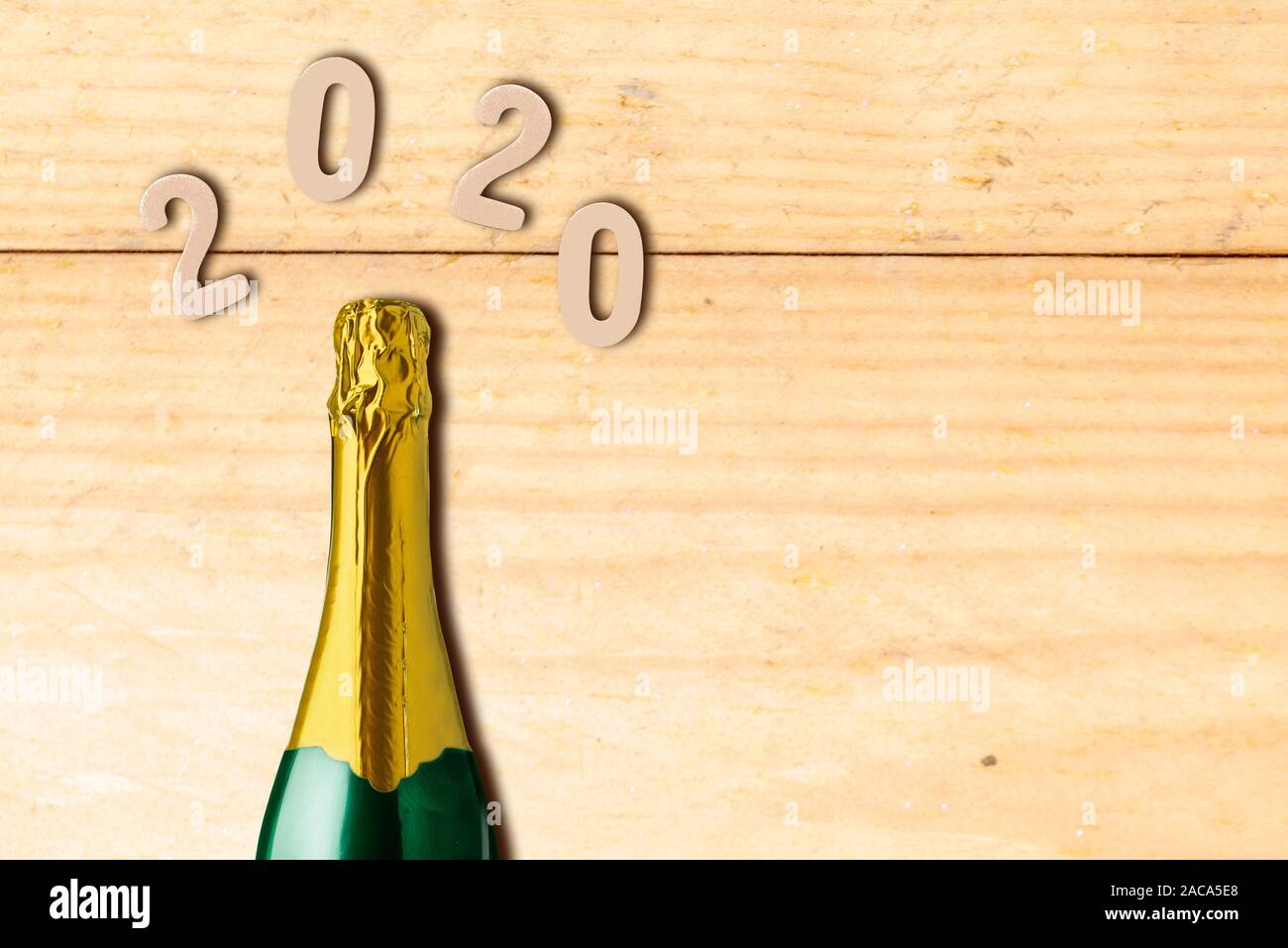 2020 on the wooden table with a champagne bottle for the new year party ...