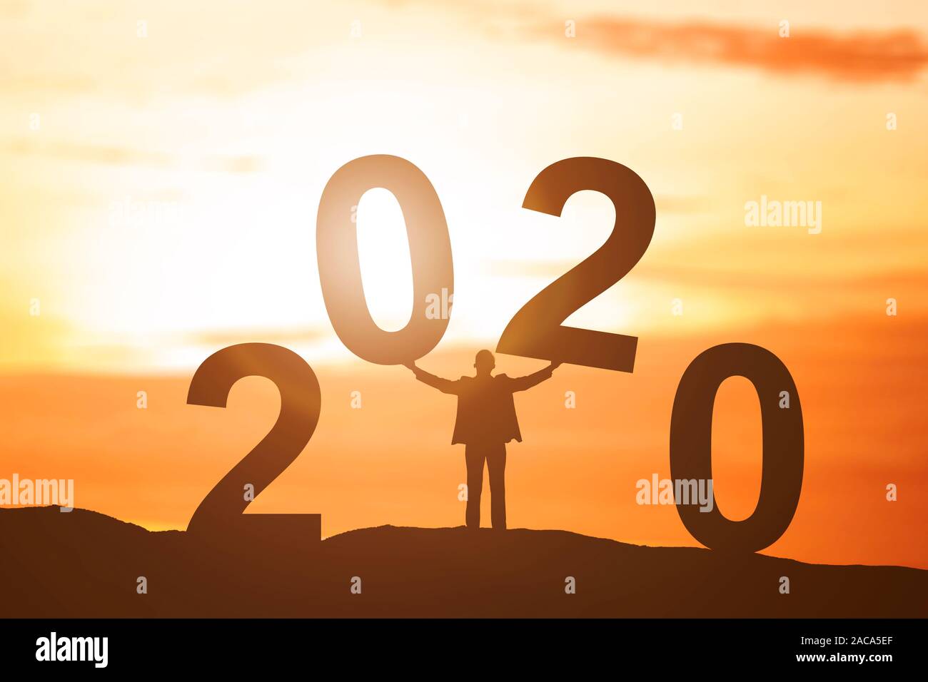 Silhouette of businessman put 2020 on the top of the hill with a sunset ...