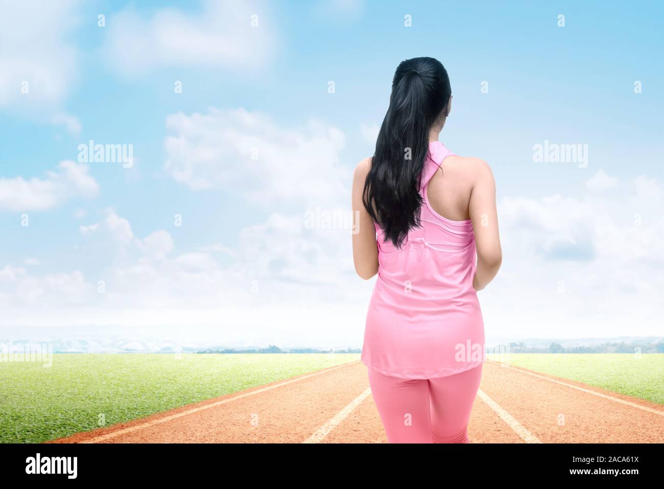 Rear view of Asian runner woman running on the running track with a ...