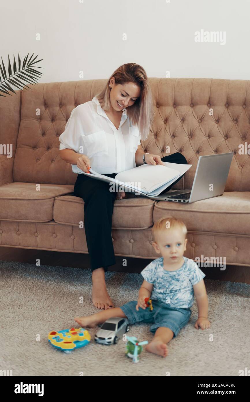 Beautiful business woman working at home. Multi-tasking, freelance and motherhood concept ...
