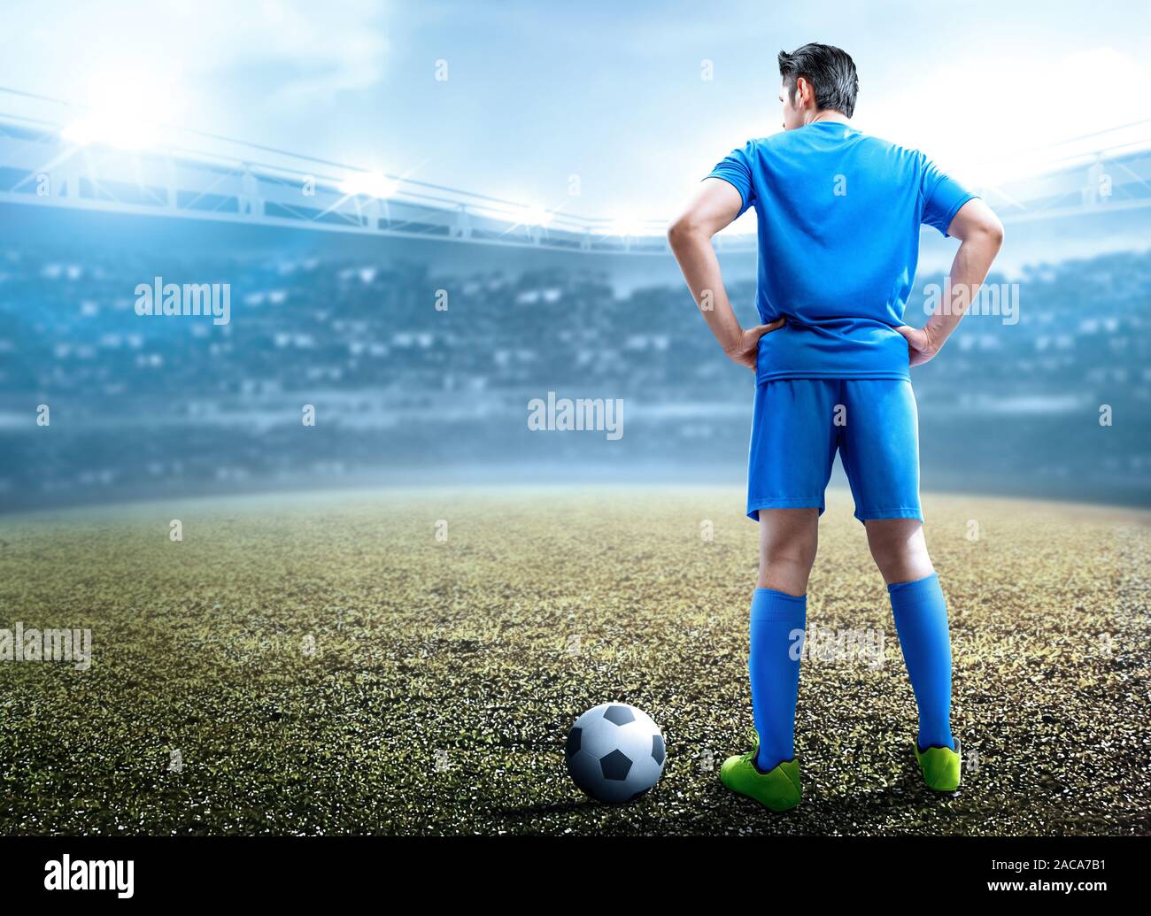 Rear view of Asian football player man standing with the ball on the ...