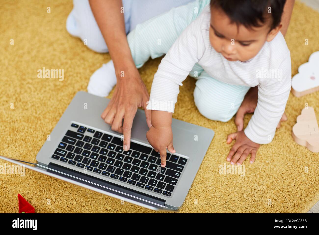 Close-up of child typing on computer keyboard on laptop with mother ...