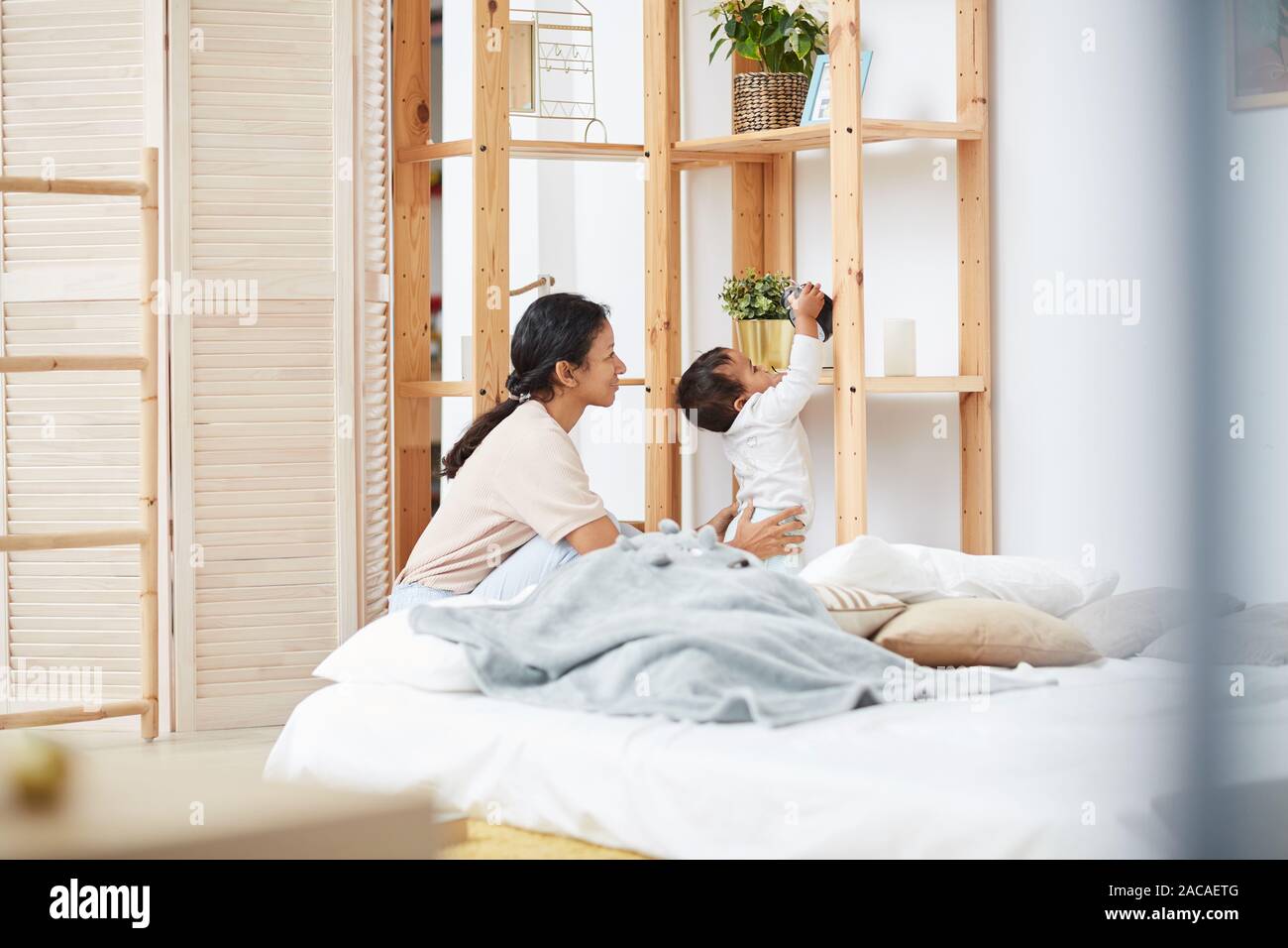 Little child taking the clock from the shelf while playing with his ...