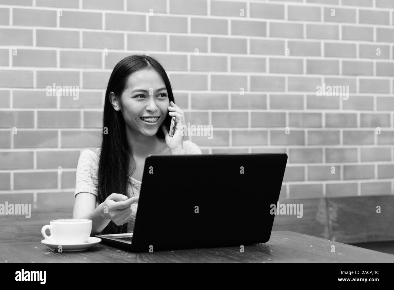 Young happy Asian teenage girl smiling and talking on mobile phone ...
