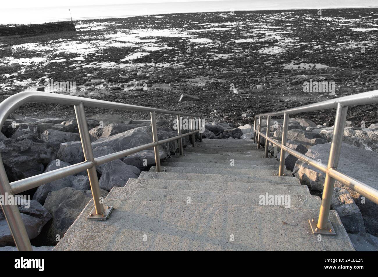 Looking down beach steps with stainless steel railing at low tide ...