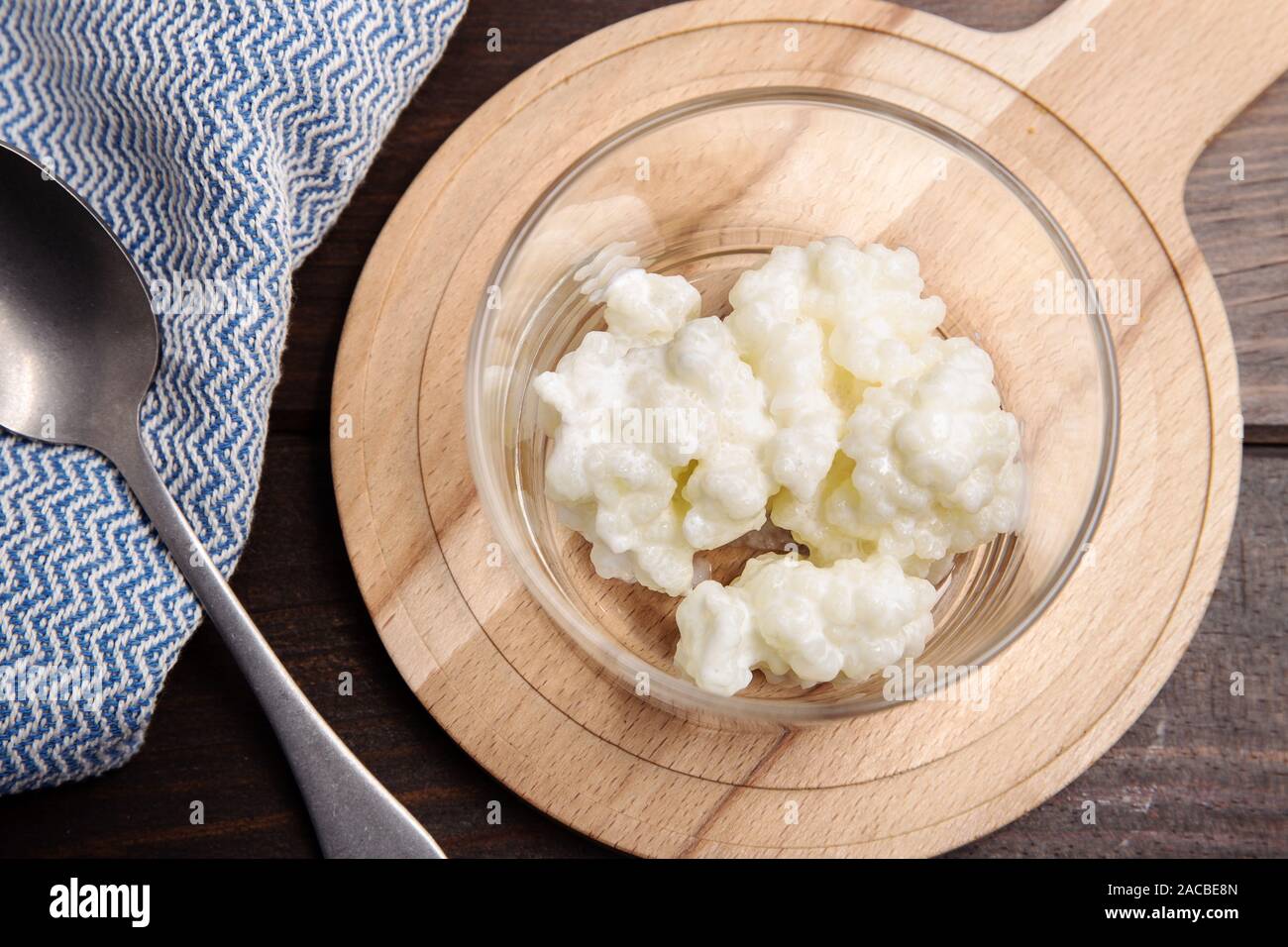 Milk kefir grains in jar on wooden table. Yeast bacterial fermentation ...