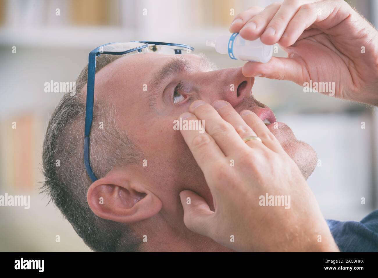 Man applying eye drops after a long sitting at computer Stock Photo - Alamy