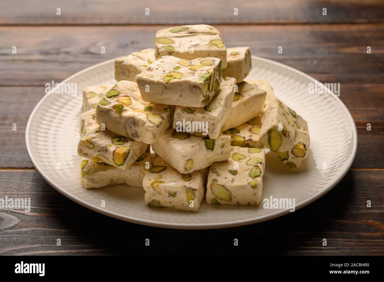 Eastern Arabic nougat sweetness with pistachios on a ceramic plate on a ...
