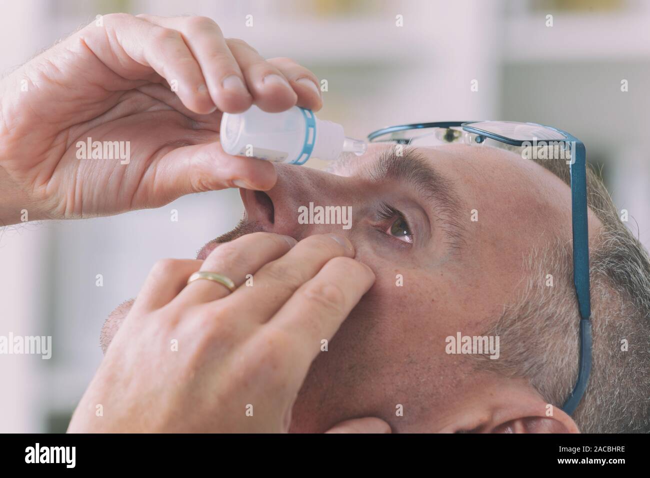 Man applying eye drops after a long sitting at computer Stock Photo - Alamy