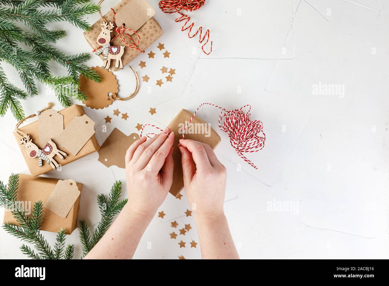 Woman's hands wrapping christmas handmade present in paper with twine ...