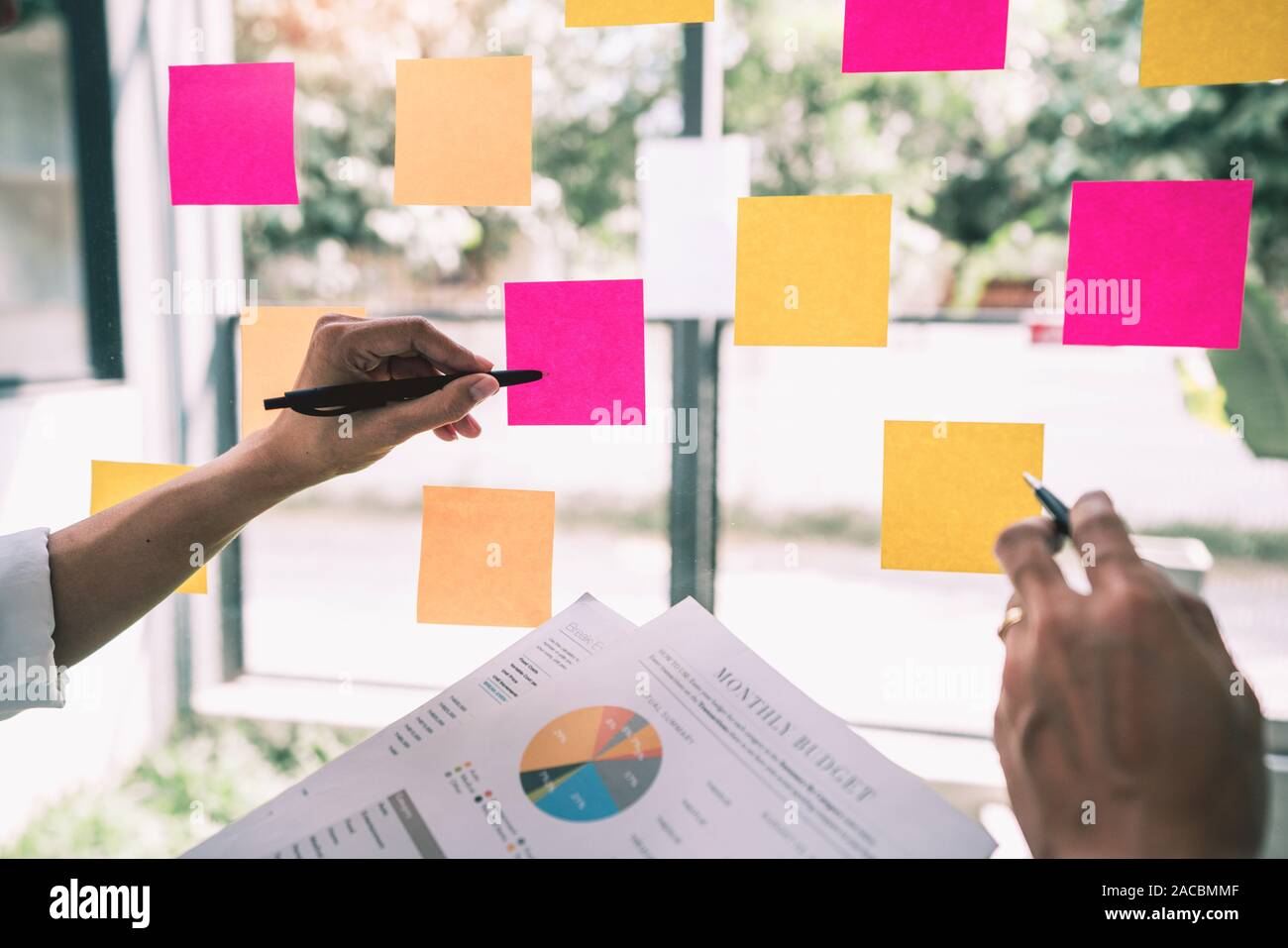 Business people meeting at office and use sticky notes on glass wall in ...