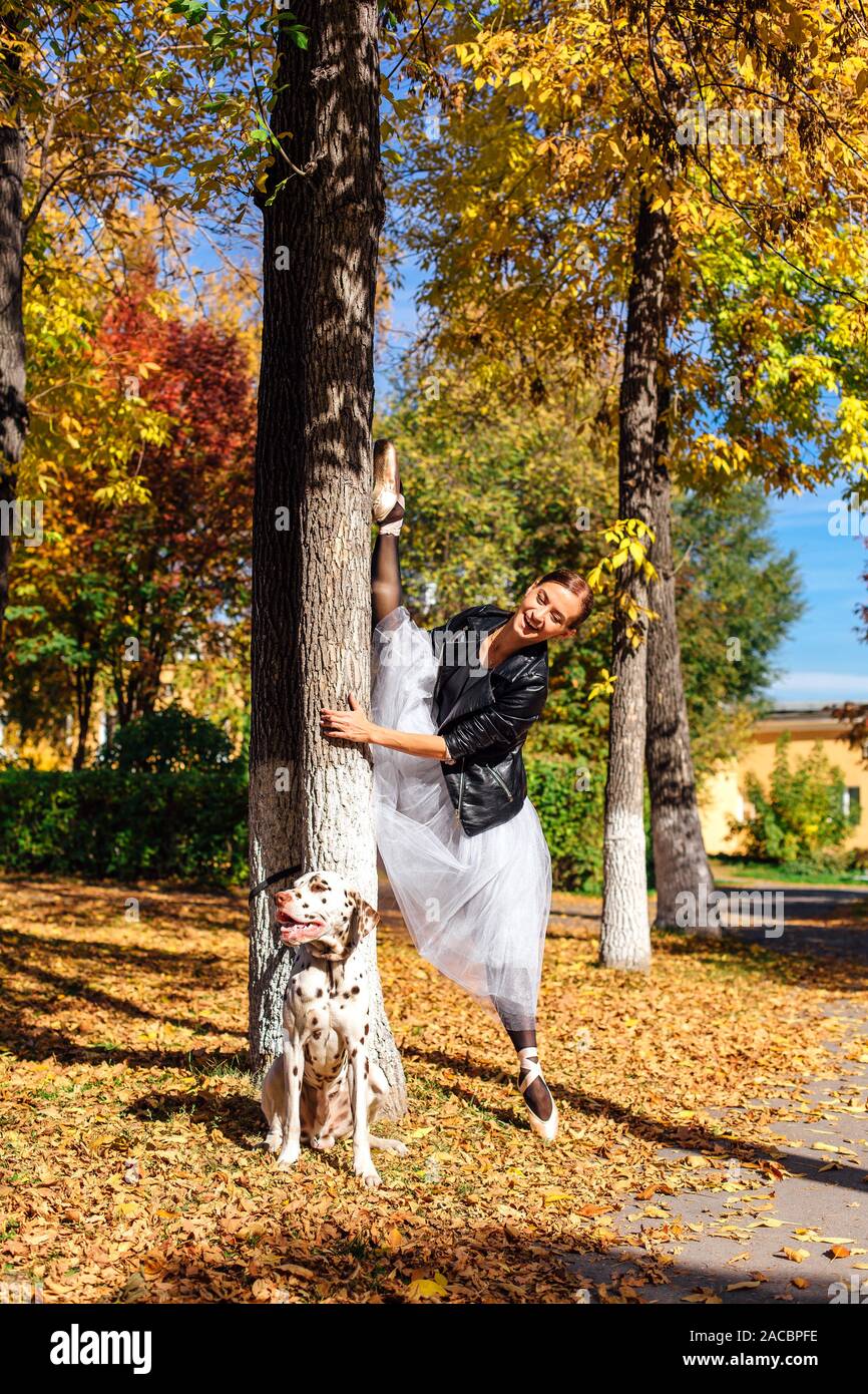 Ballerina with Dalmatian dog in the Park. Woman ballerina in a white ...
