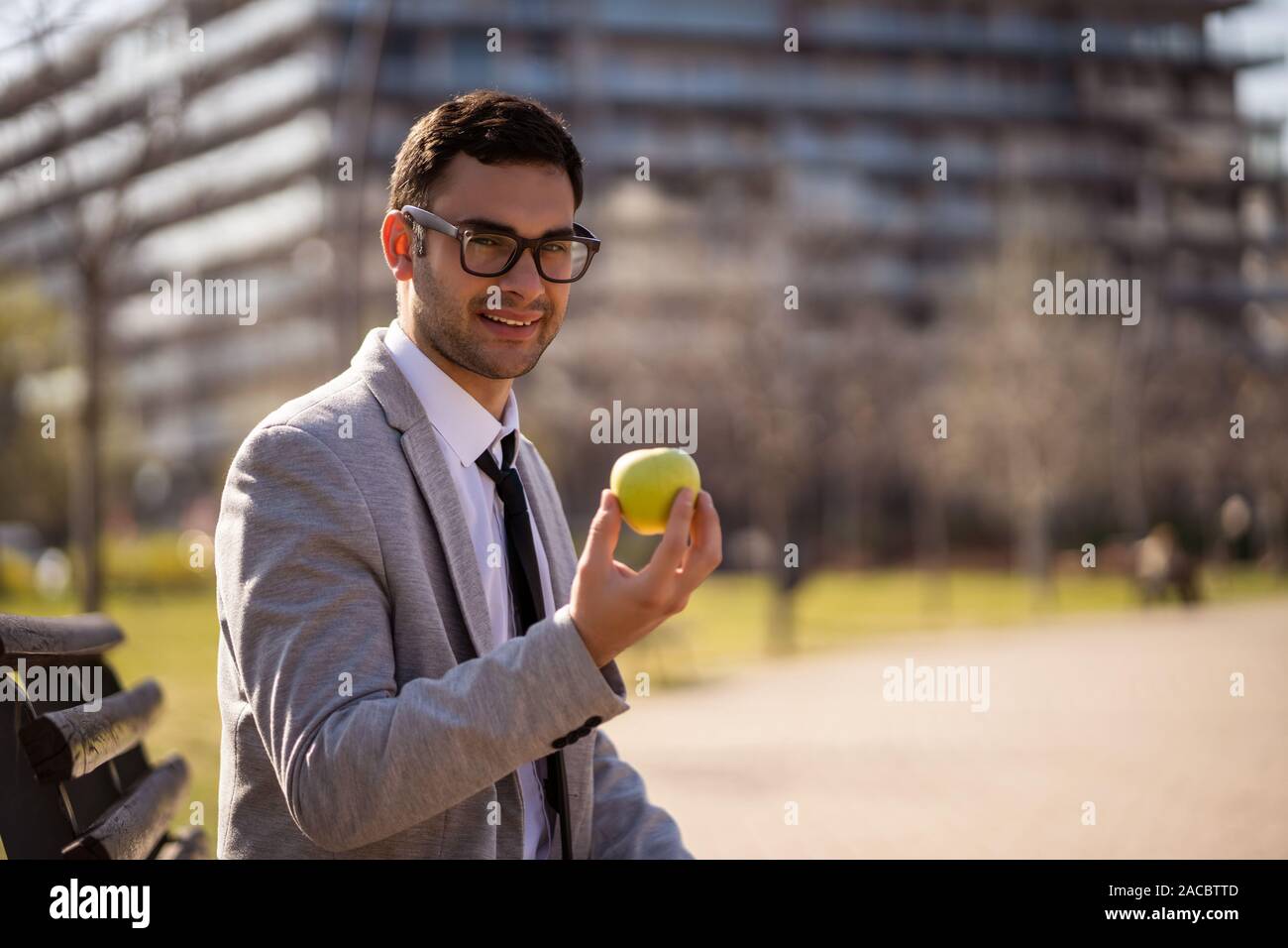 Young businessman is eating apple in park after work Stock Photo - Alamy