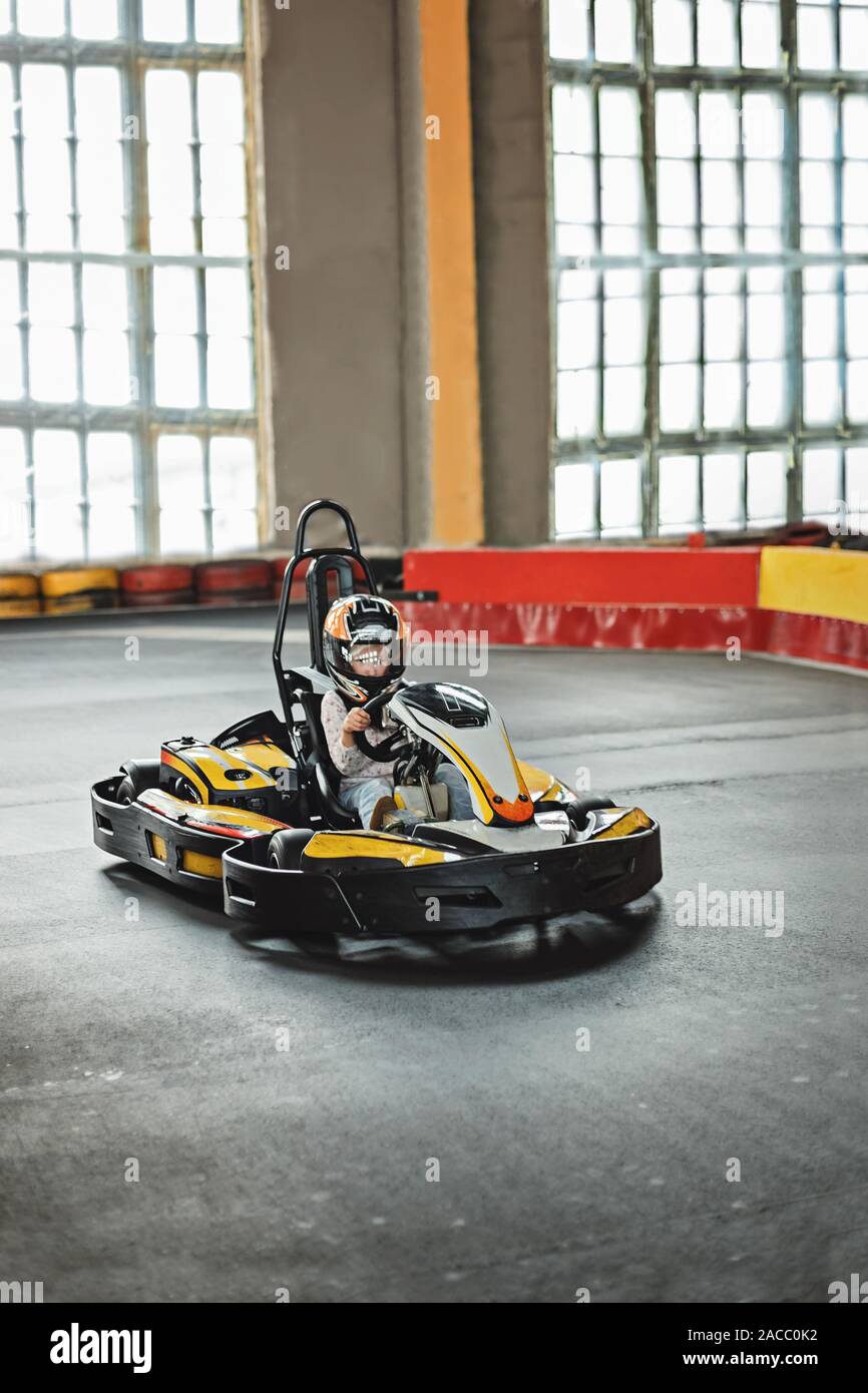 Children`s entertainment indoors. Girl driving go kart on the track ...