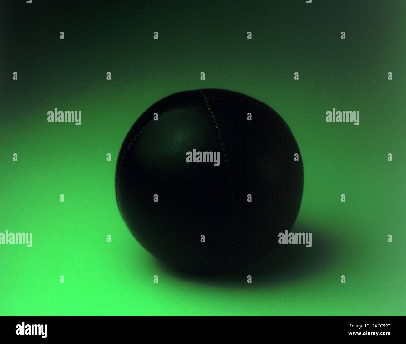 Red ball seen under green light. The ball appears black as its surface ...