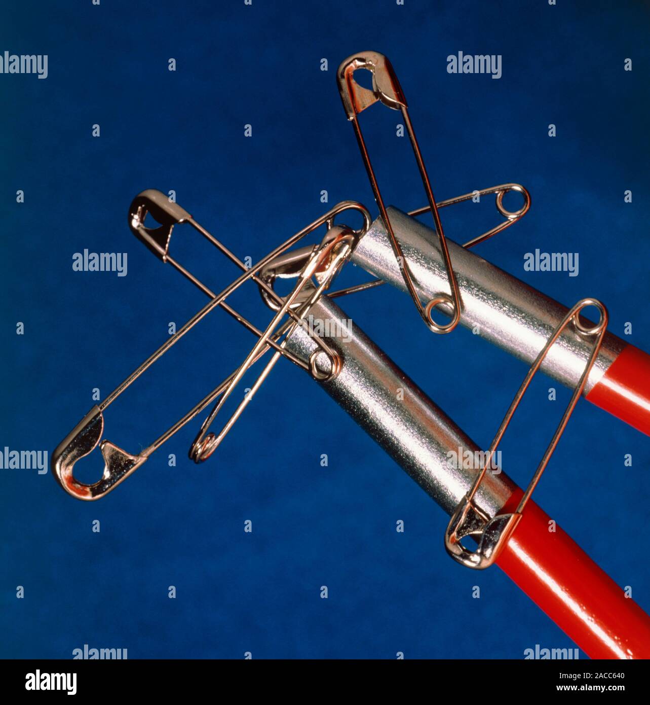 A horseshoe magnet holding some safety-pins. Magnetic objects are ...