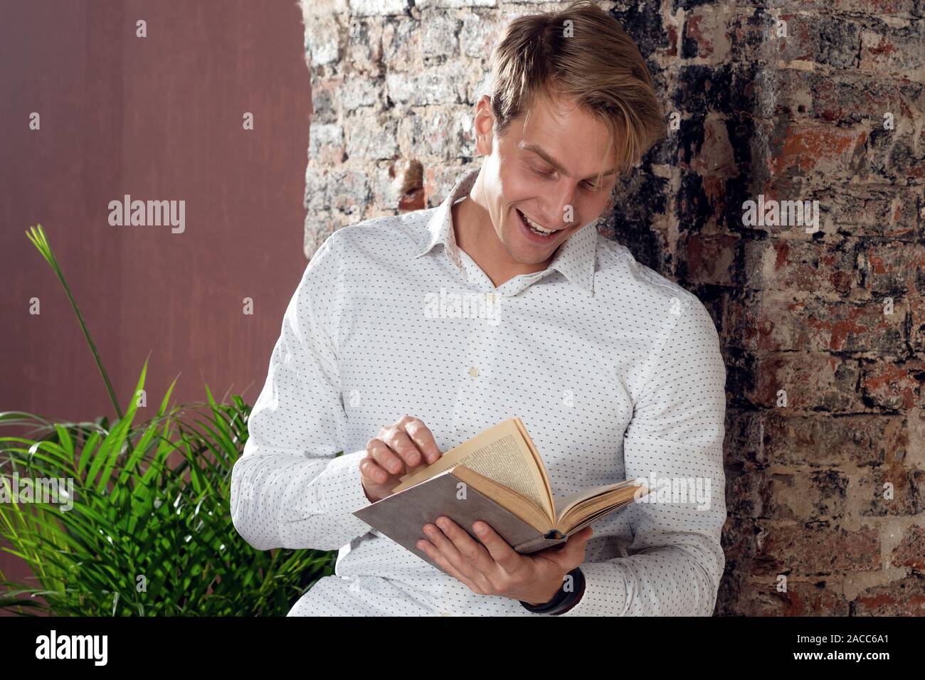 A young man in a white shirt reading a book. Business literature for ...