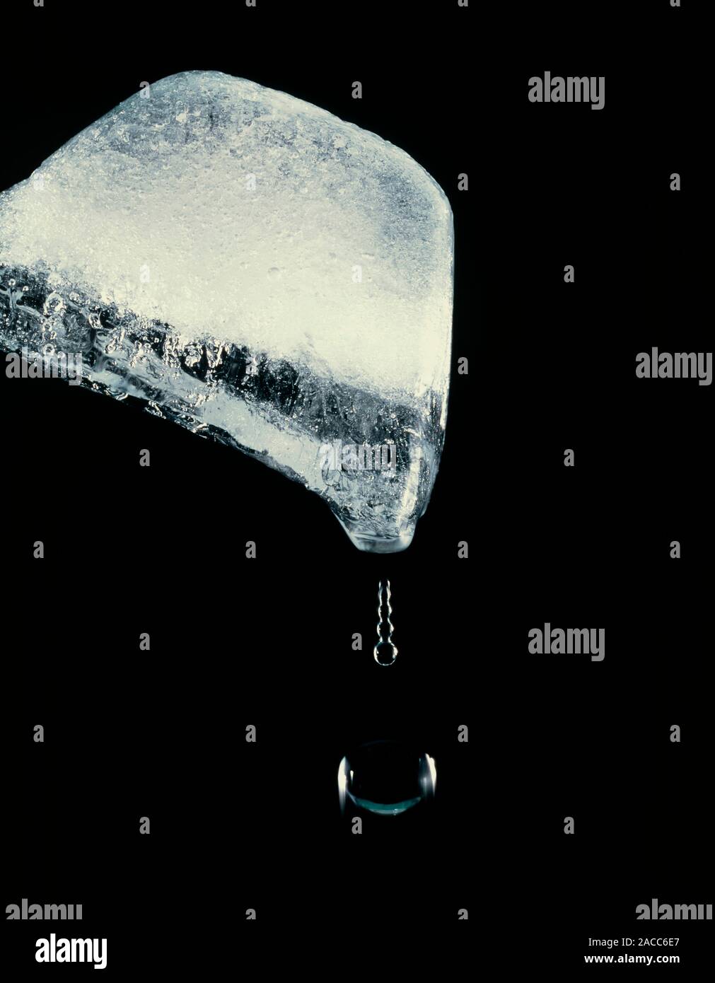 Melting ice. View of a drop of water falling from the edge of a block ...