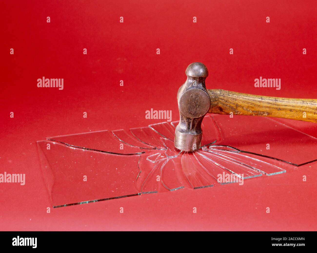 Glass and hammer. Image 2 of 2. A pane of glass has shattered after ...