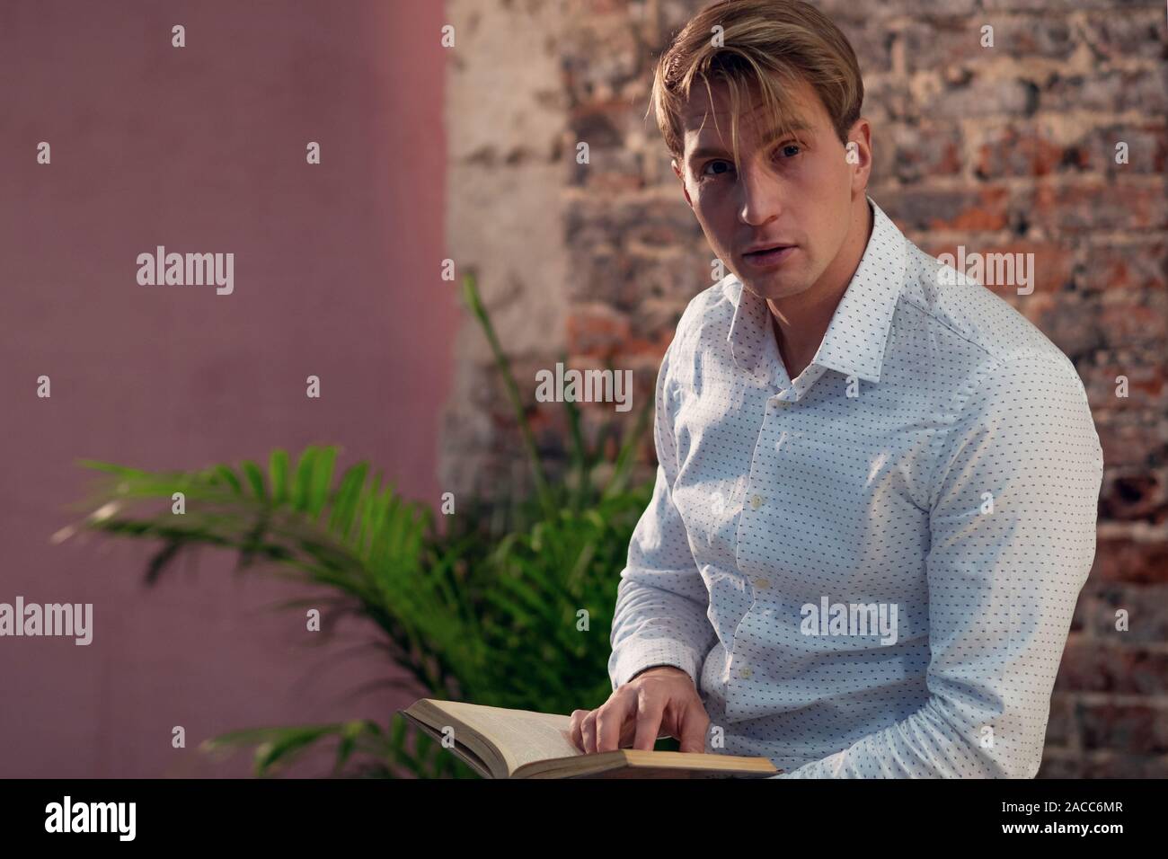 A young man in a white shirt reading a book. Business literature for ...