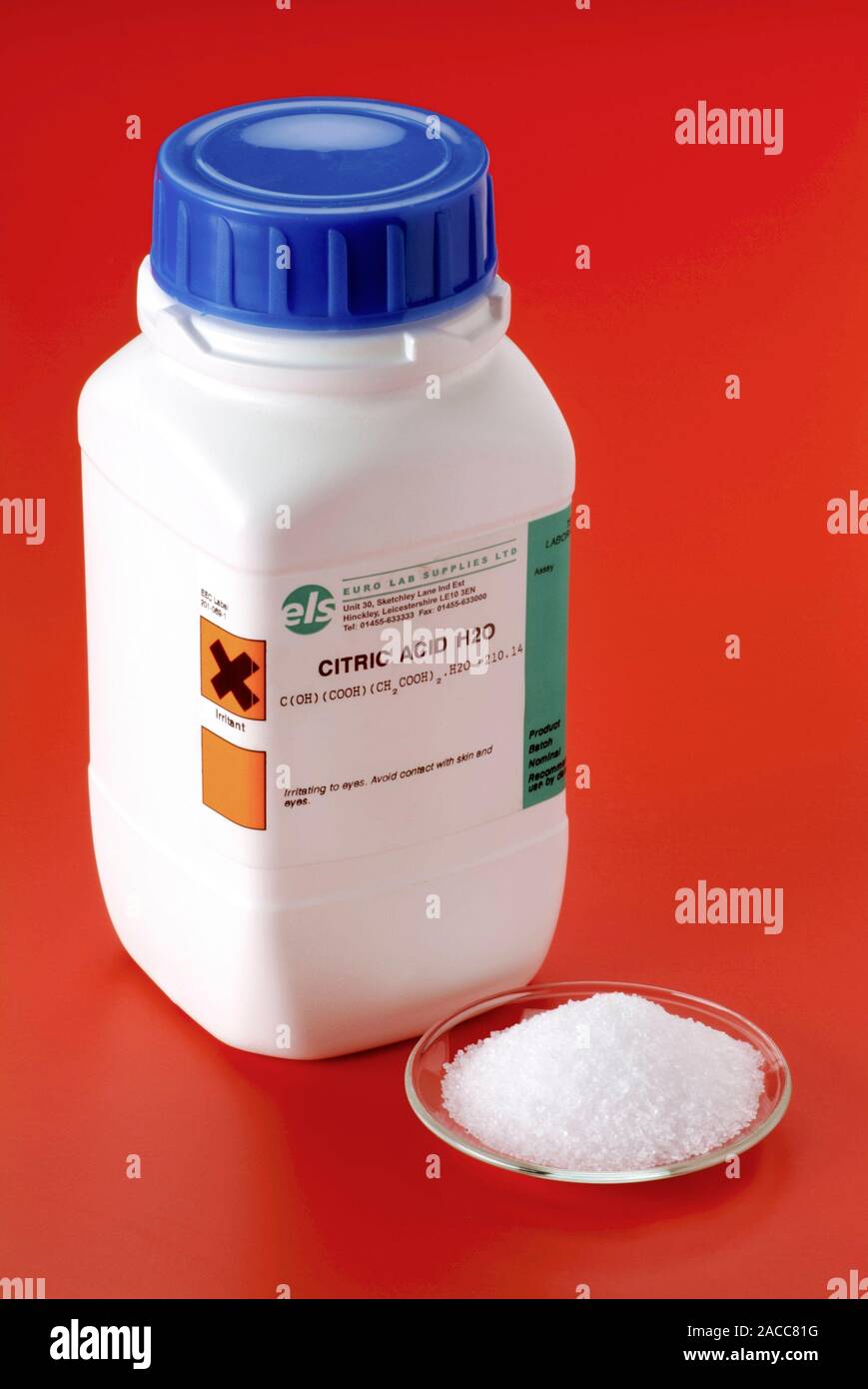Citric acid. A plastic bottle containing citric acid and a watch glass ...
