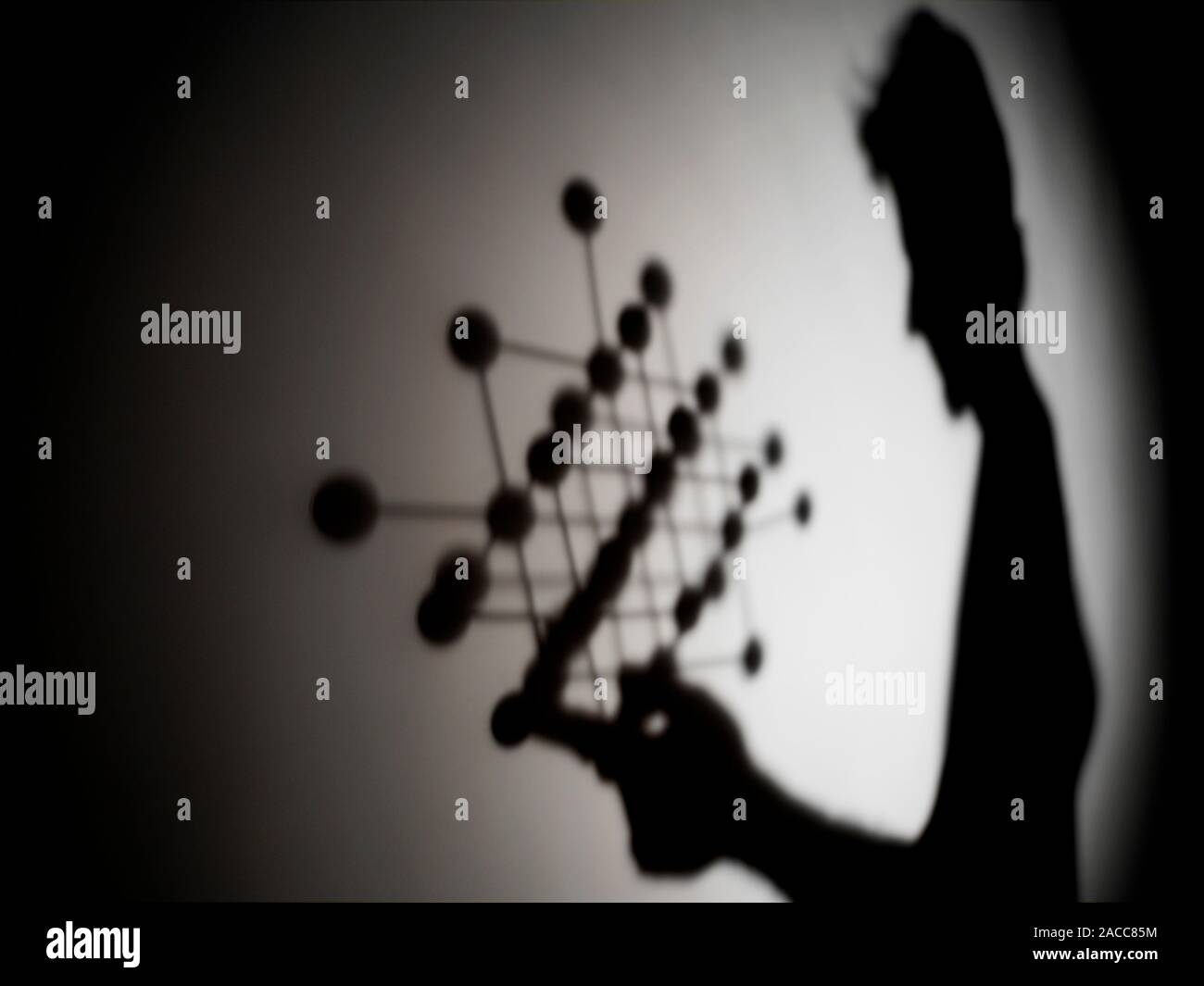 Molecular model. Shadow of a person holding a plastic molecular model ...