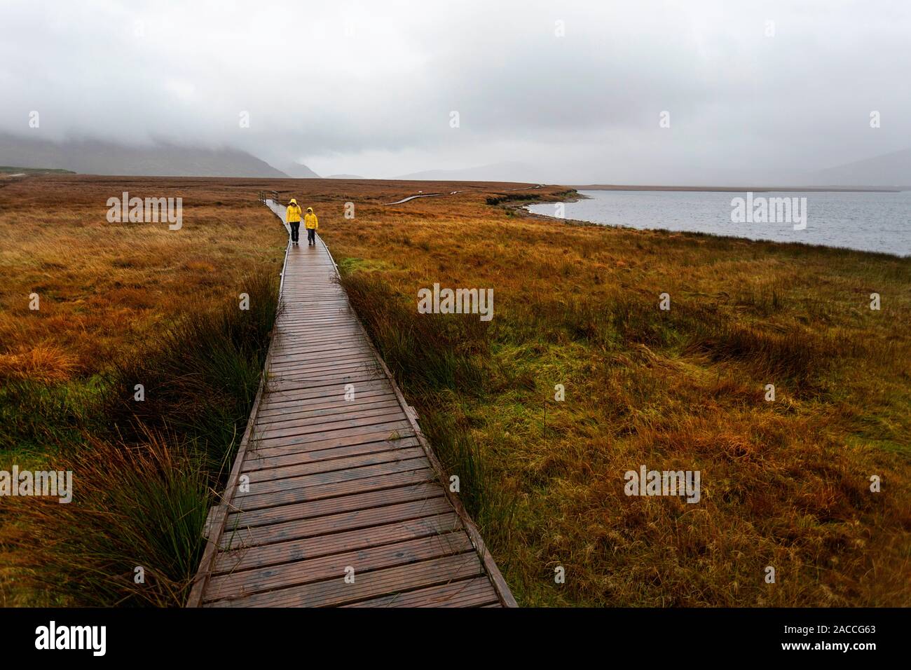 Mother and son walking on signed wooden walkway in Ballycroy National ...