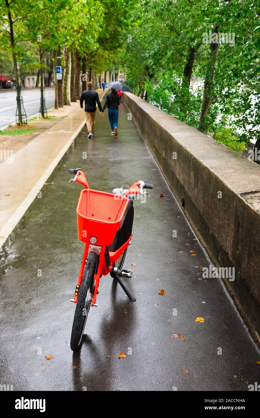 Red electric bicycle on side walk during rainy day, ecological ...