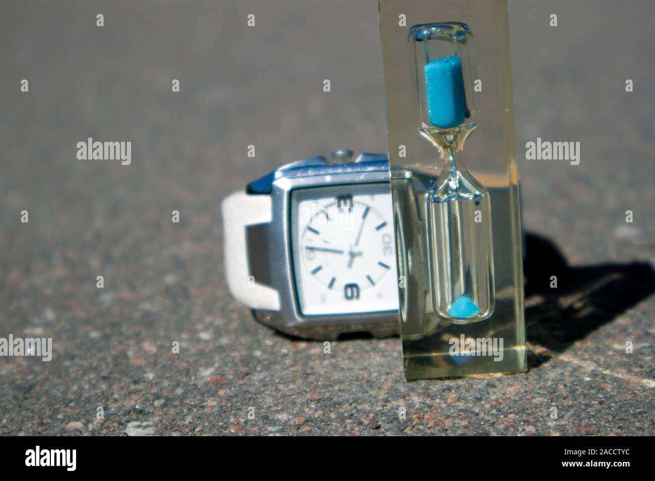 Transparent hourglass with blue sand and watch with white clock face ...