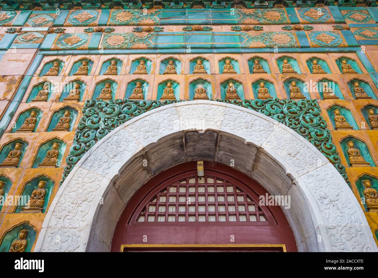 The wall above the doorway, decorated with many oriental statues of ...