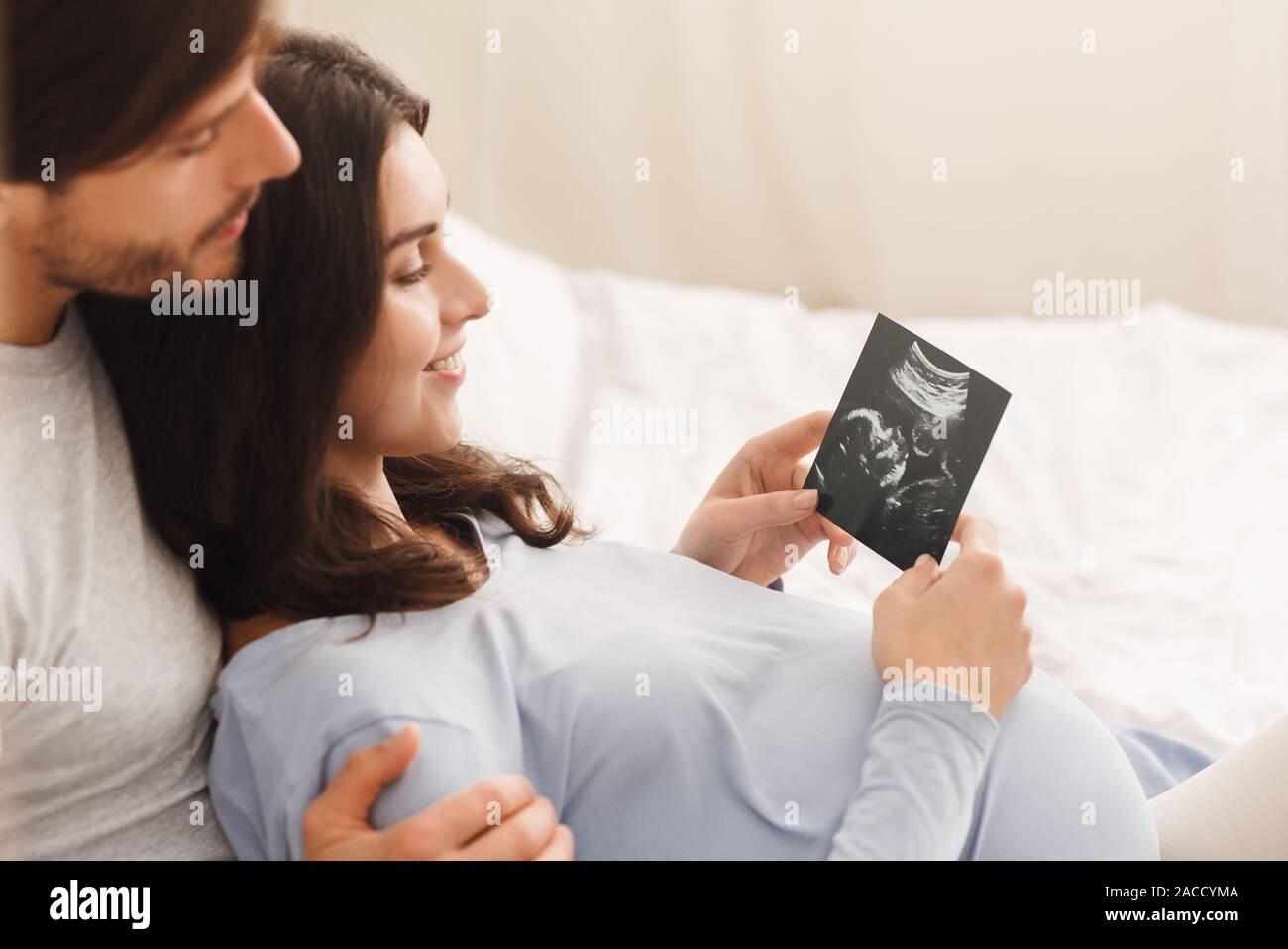 Happy pregnant woman and her husband looking at sonogram picture Stock ...