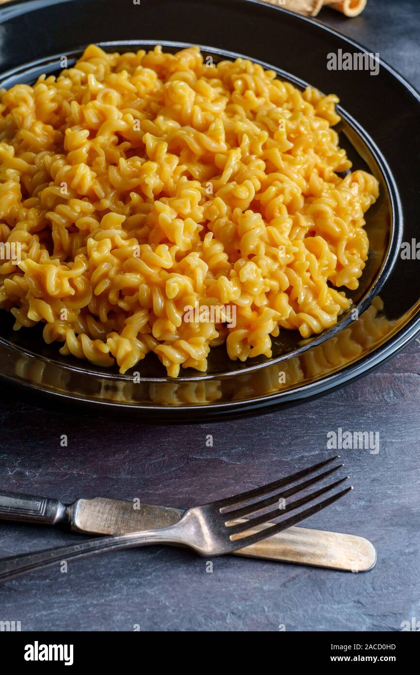 Delicious spiral macaroni and cheddar cheese on black plate Stock Photo ...