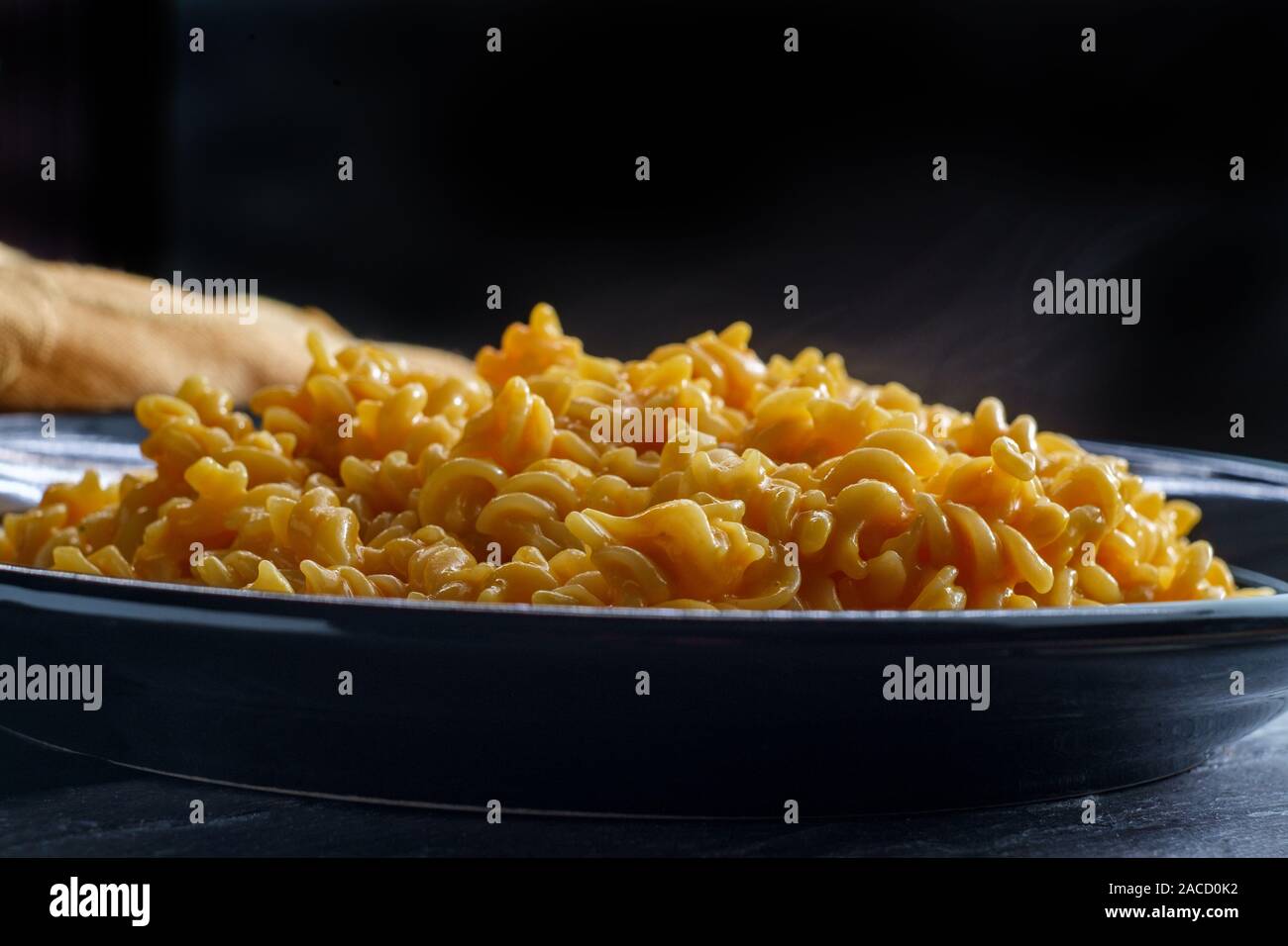 Delicious spiral macaroni and cheddar cheese on black plate Stock Photo ...