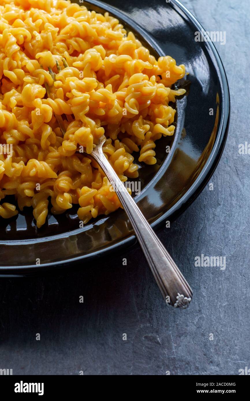Delicious spiral macaroni and cheddar cheese on black plate Stock Photo ...