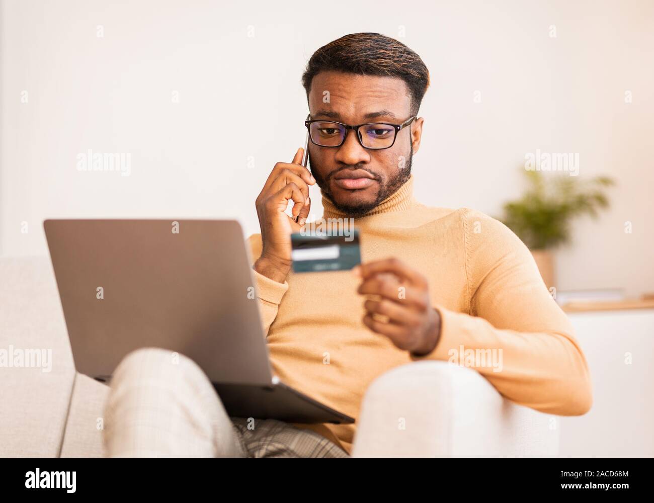 Guy Calling By Phone Using Credit Card And Laptop Indoor Stock Photo ...