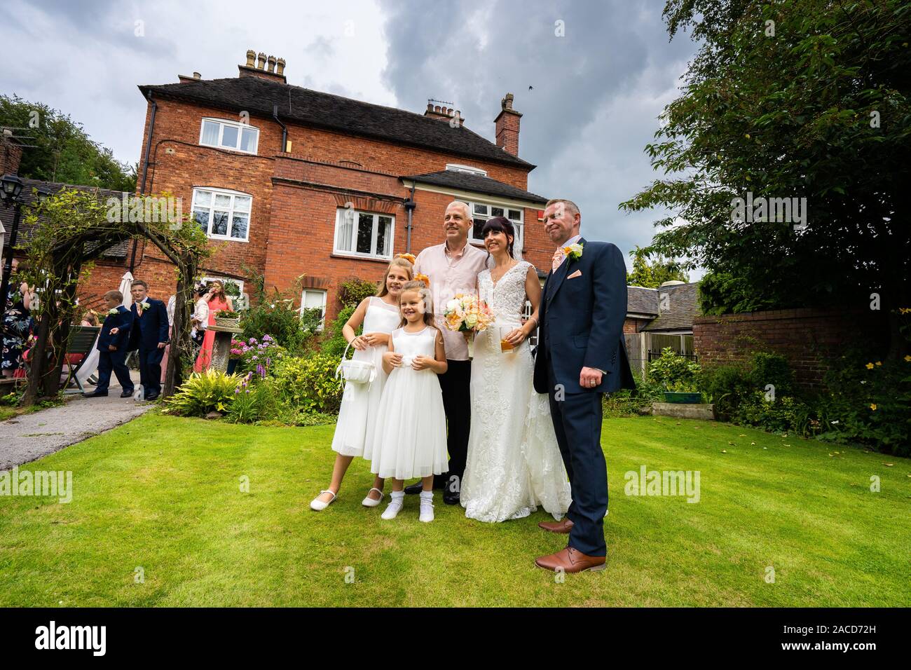 Bride, Groom and wedding guests pose for picture outside at the Manor ...