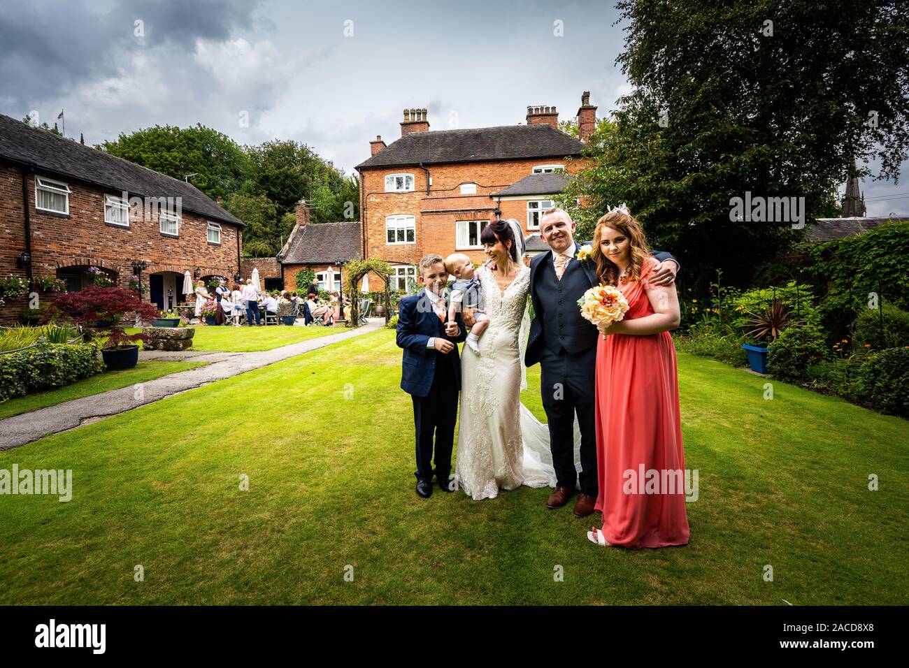 Bride, Groom and wedding guests pose for picture outside at the Manor ...