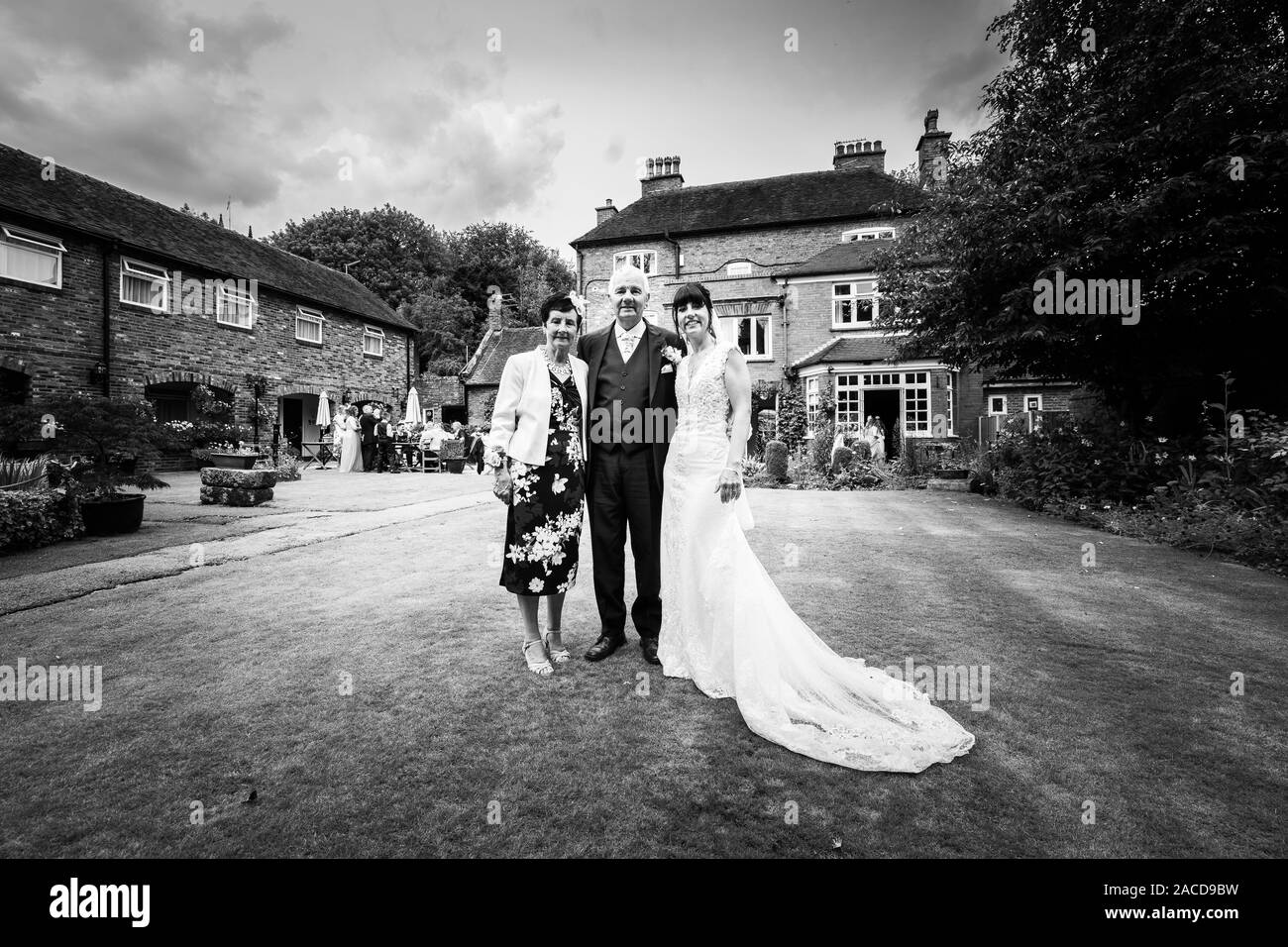 Bride, Groom and wedding guests pose for picture outside at the Manor ...