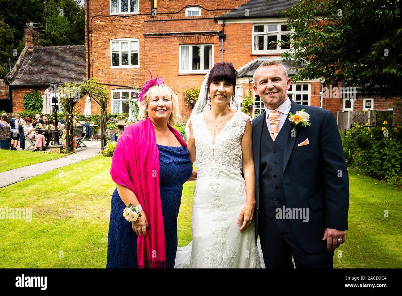 Bride, Groom and wedding guests pose for picture outside at the Manor ...