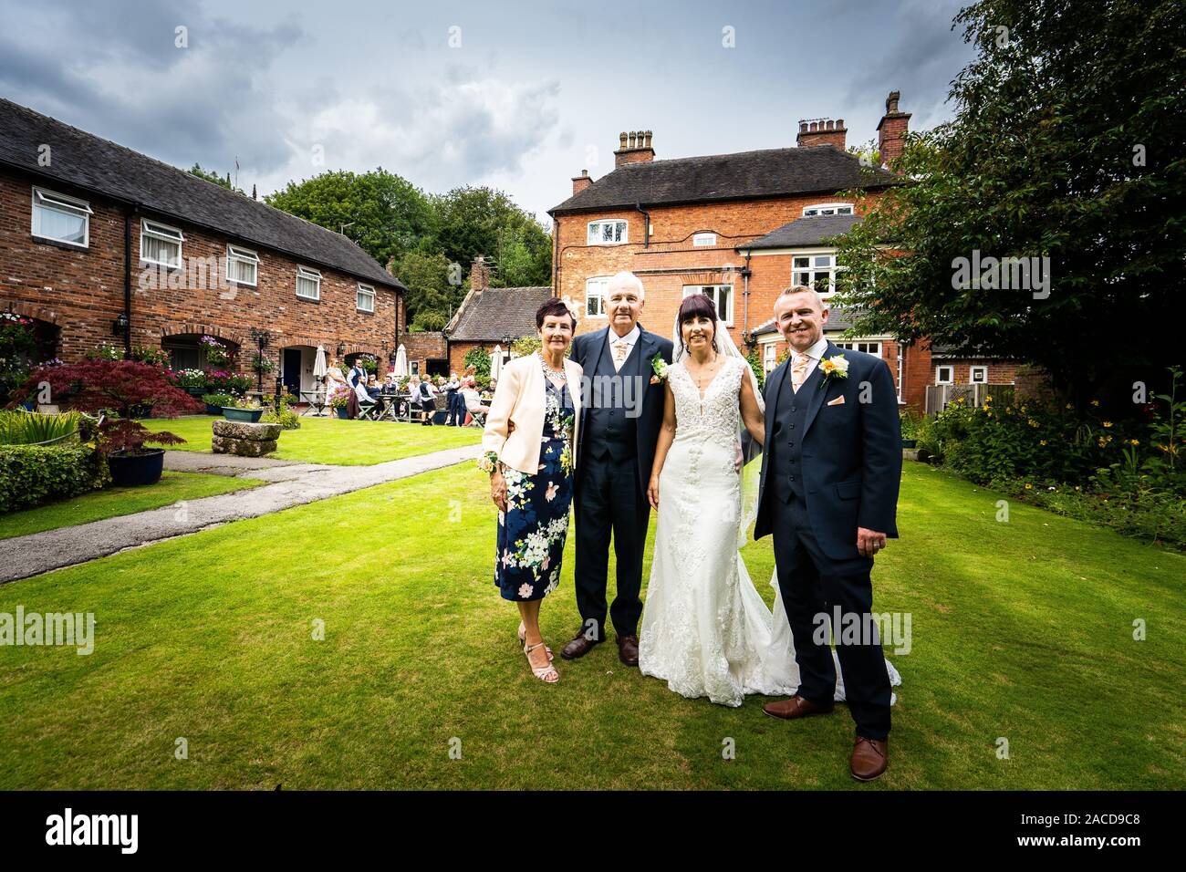 Bride, Groom and wedding guests pose for picture outside at the Manor ...