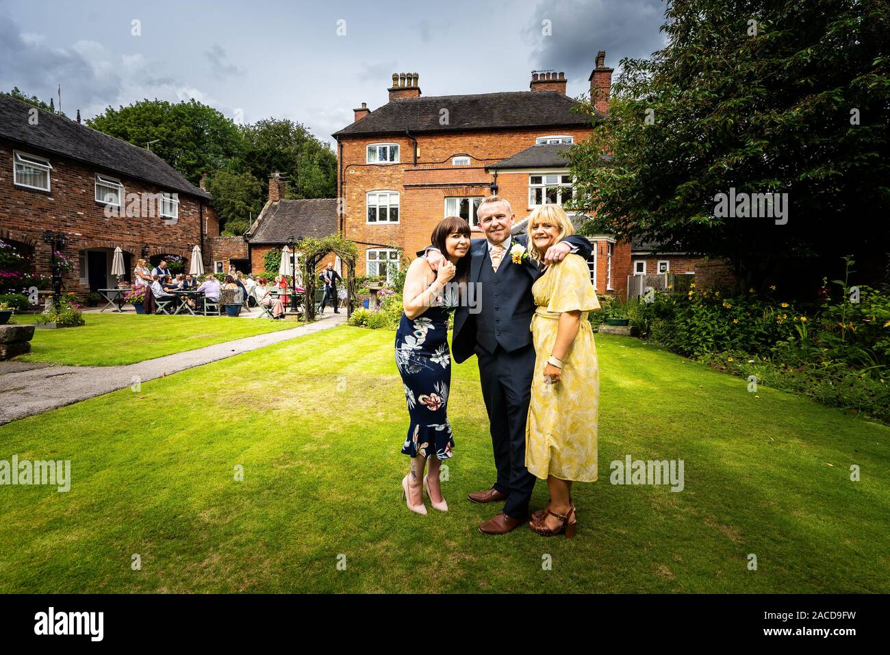 Bride, Groom and wedding guests pose for picture outside at the Manor ...