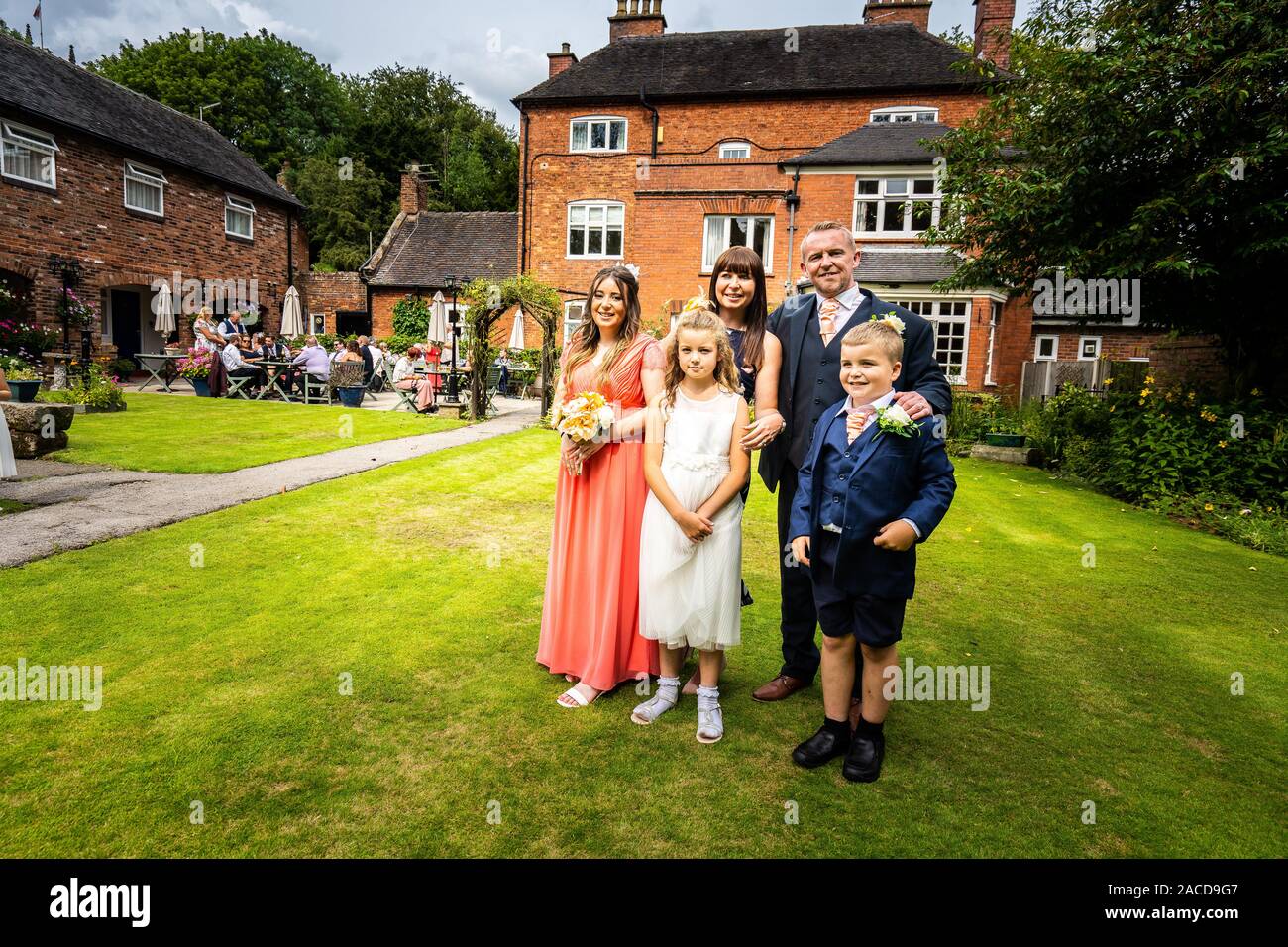 Bride, Groom and wedding guests pose for picture outside at the Manor ...
